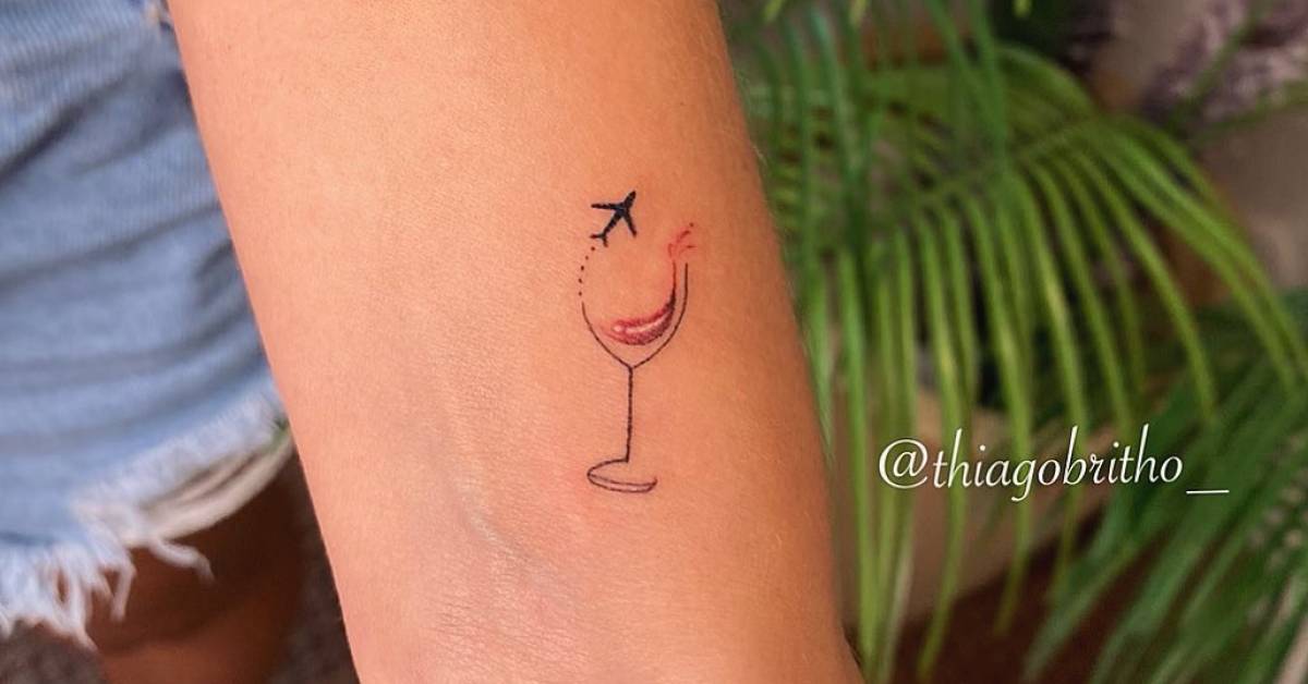 Fine line wine glass and airplane tattoo on the wrist.