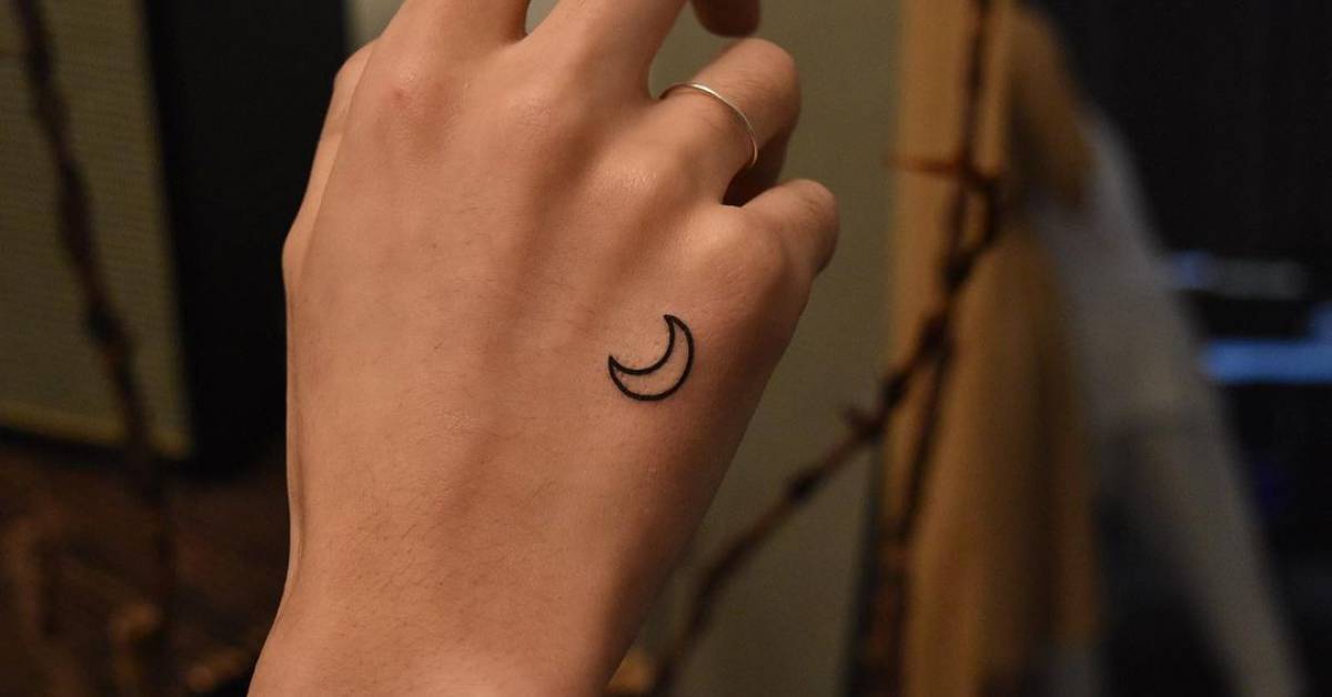 Minimalist crescent moon tattoo on the hand.