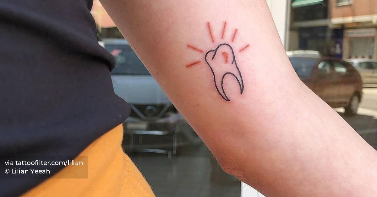 Hand poked tooth tattoo on the inner arm.