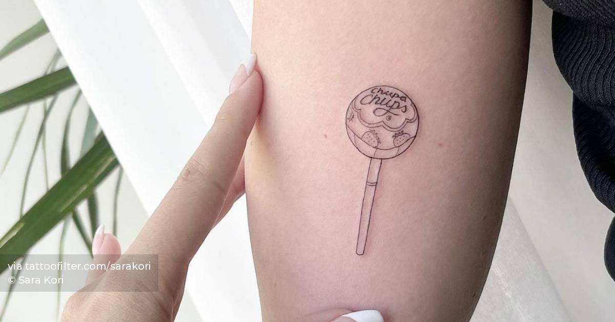 Fine line chupa chups tattoo on the inner arm.