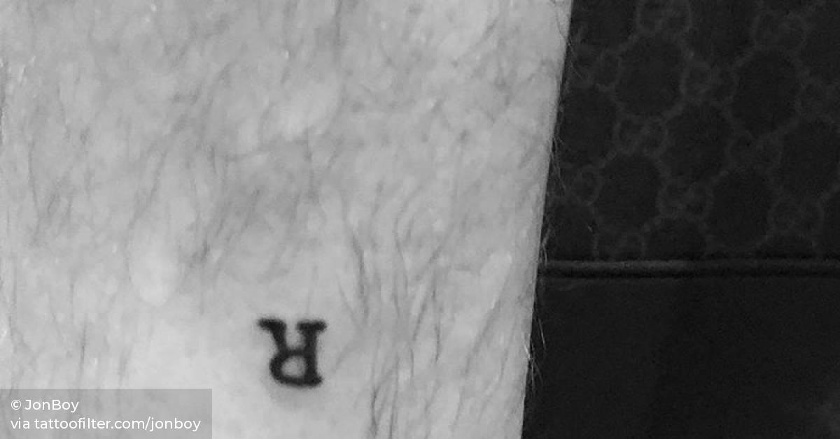 Upside down R letter tattoo on the ankle.