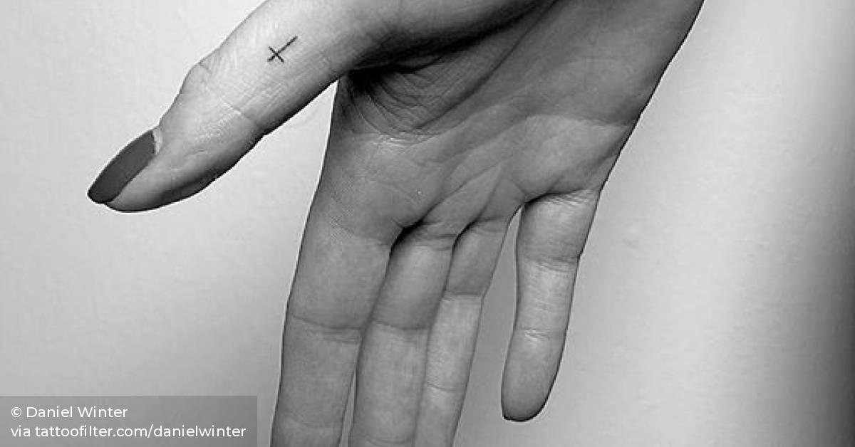 Tiny cross tattoo on the thumb.