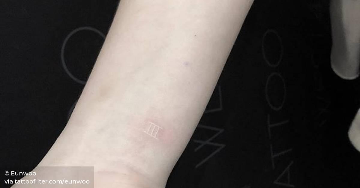 White ink three in roman numerals tattoo on the right
