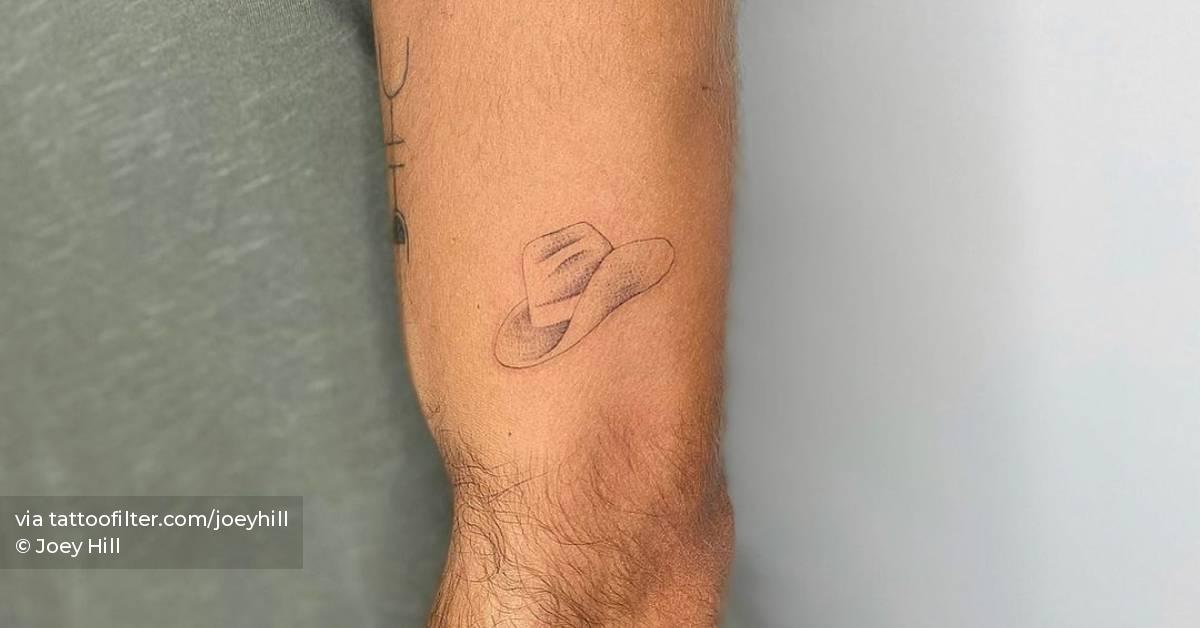 Micro-realistic hat tattoo on the upper arm.