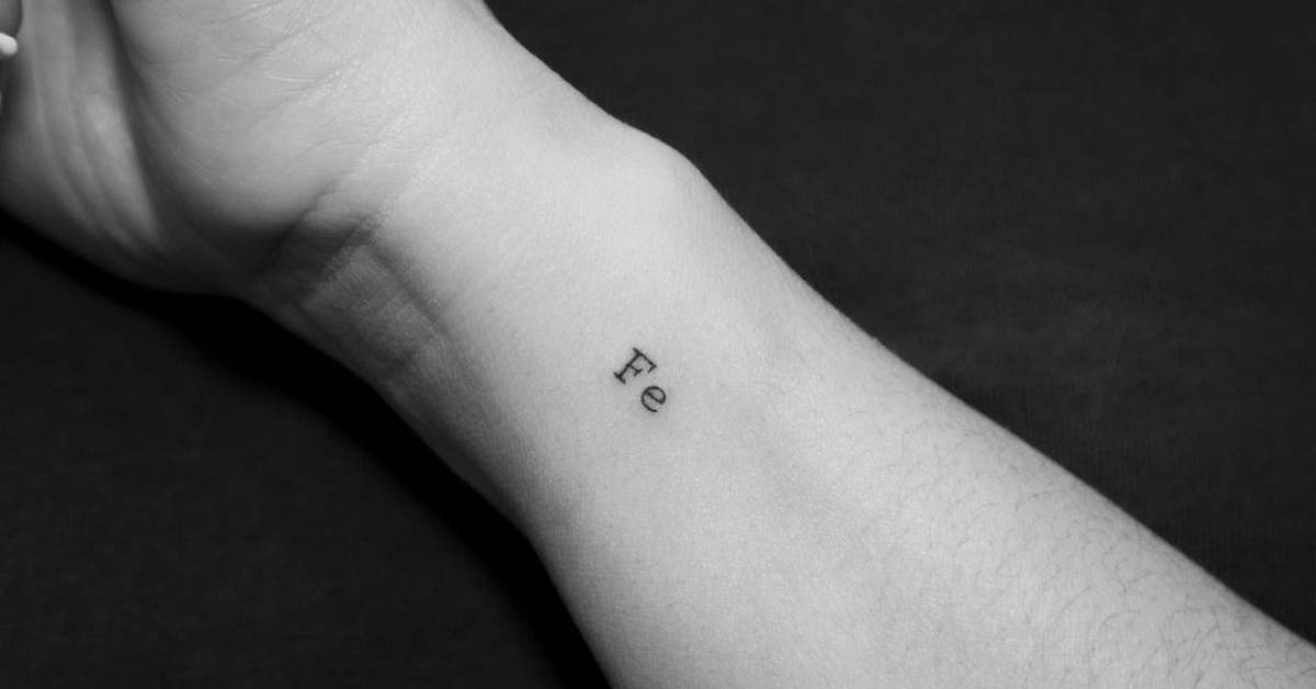 "Fe" lettering tattoo on the wrist,