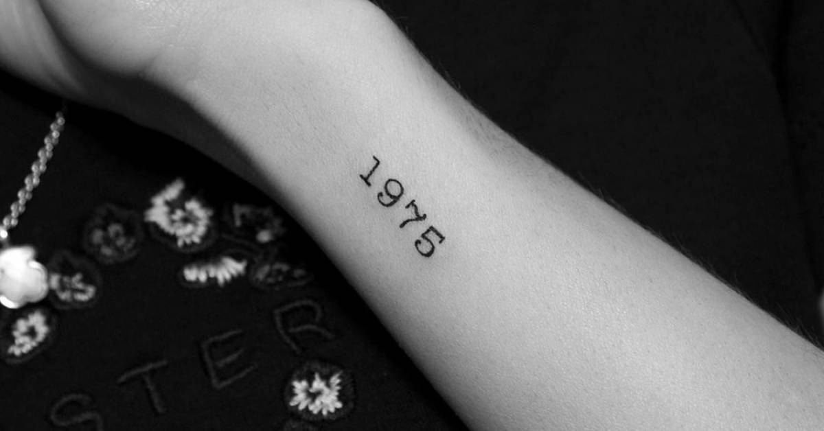 "1975" lettering tattoo on the wrist.