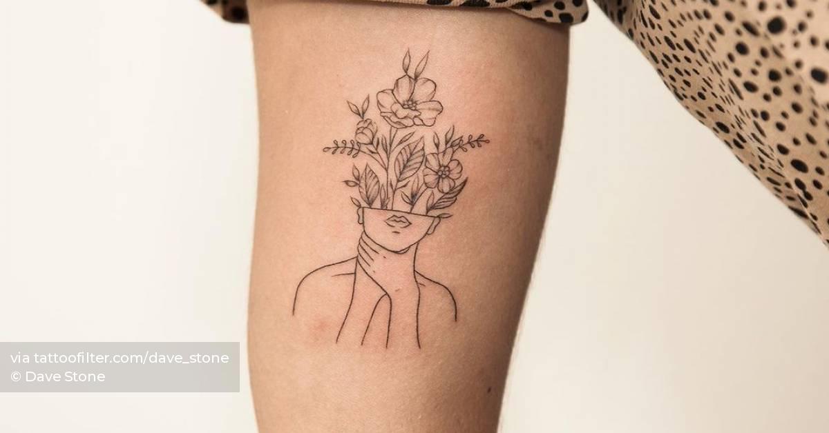 Fine line flower head woman tattoo on the inner arm.