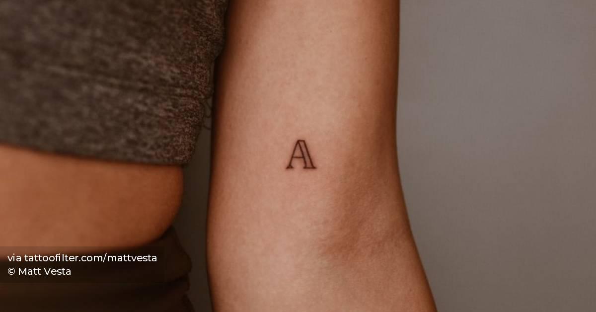 Minimalist letter "A" tattoo on the inner arm.