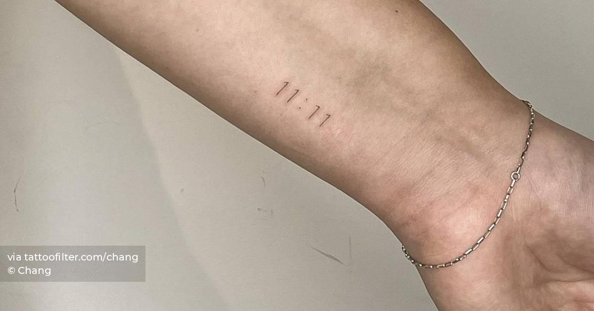 "11:11" lettering tattoo on the wrist.