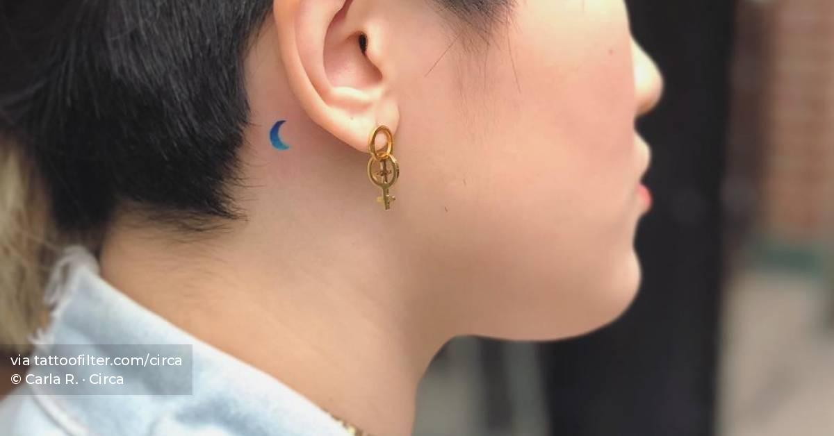 Minimalist crescent moon tattoo behind the ear.