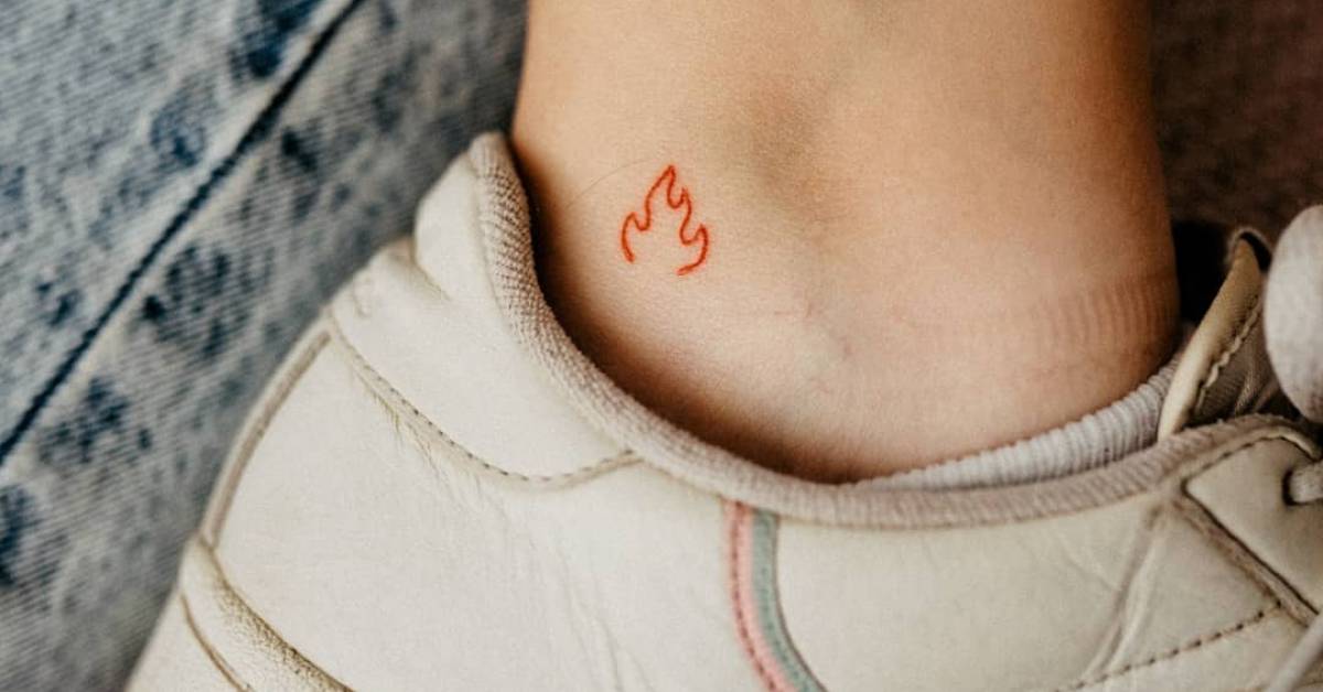 Minimalist red flame tattoo on the ankle.