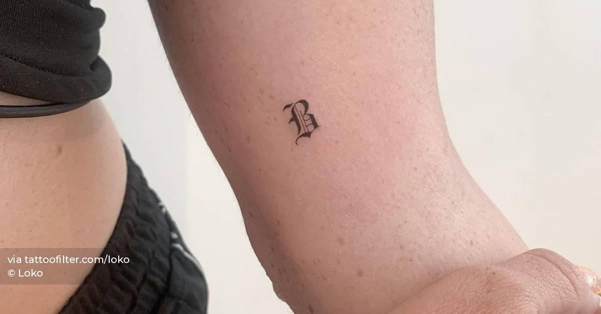 Minimalist letter "B" tattoo on the inner arm.