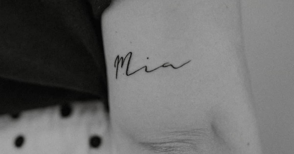 "Mia" lettering tattoo on the tricep.