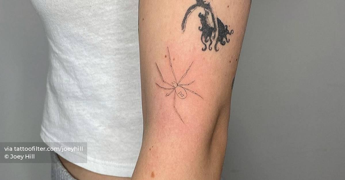 Single needle spider tattoo on the upper arm.