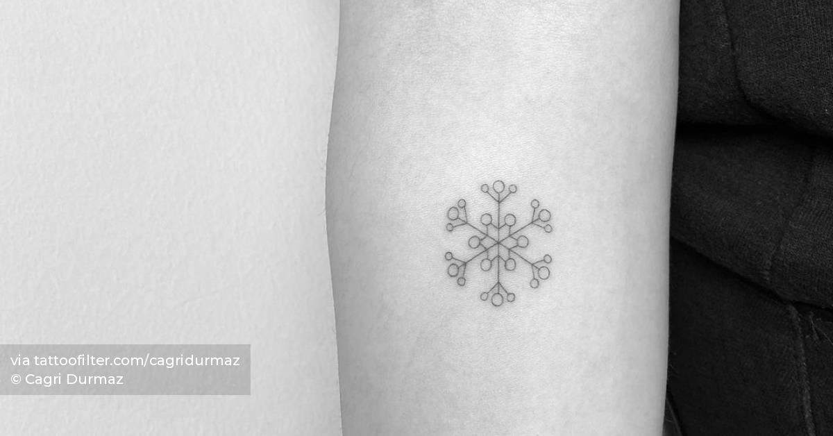 Fine line snowflake tattoo on the inner forearm.