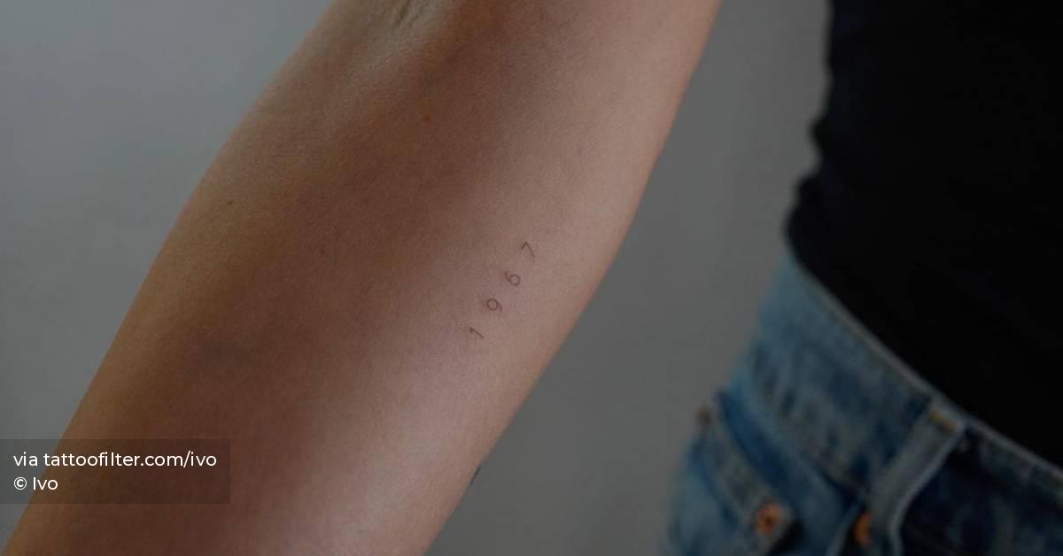 "1967" lettering tattoo on the inner forearm.