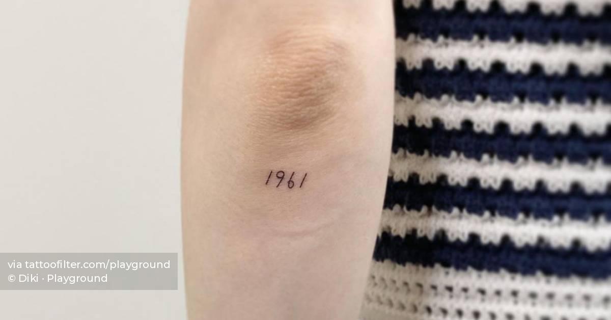 "1961" lettering tattoo on the elbow.