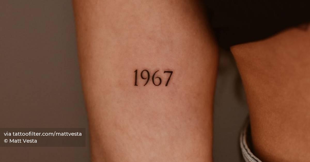 "1967" lettering tattoo on the inner arm.