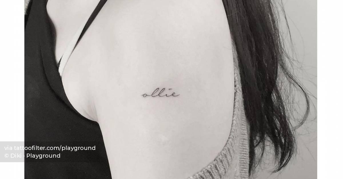 "Ollie" lettering tattoo on the upper arm.