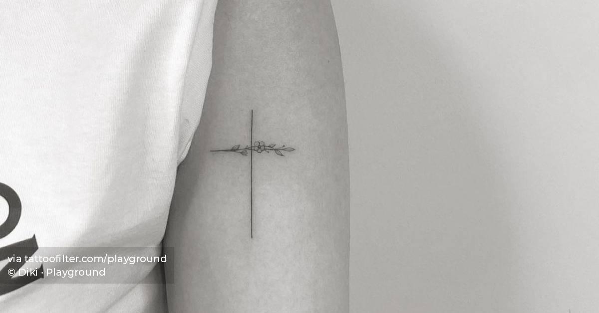 Fine line flower cross tatto on the bicep.