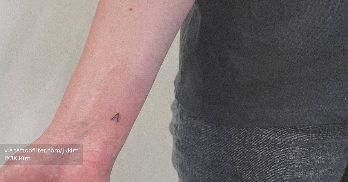Minimalist letter "A" tattoo on the wrist.