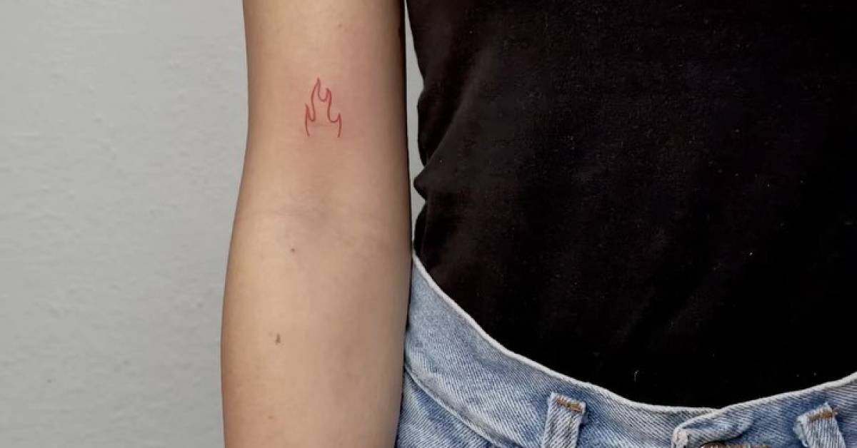 Minimalist red fire tattoo on the bicep.