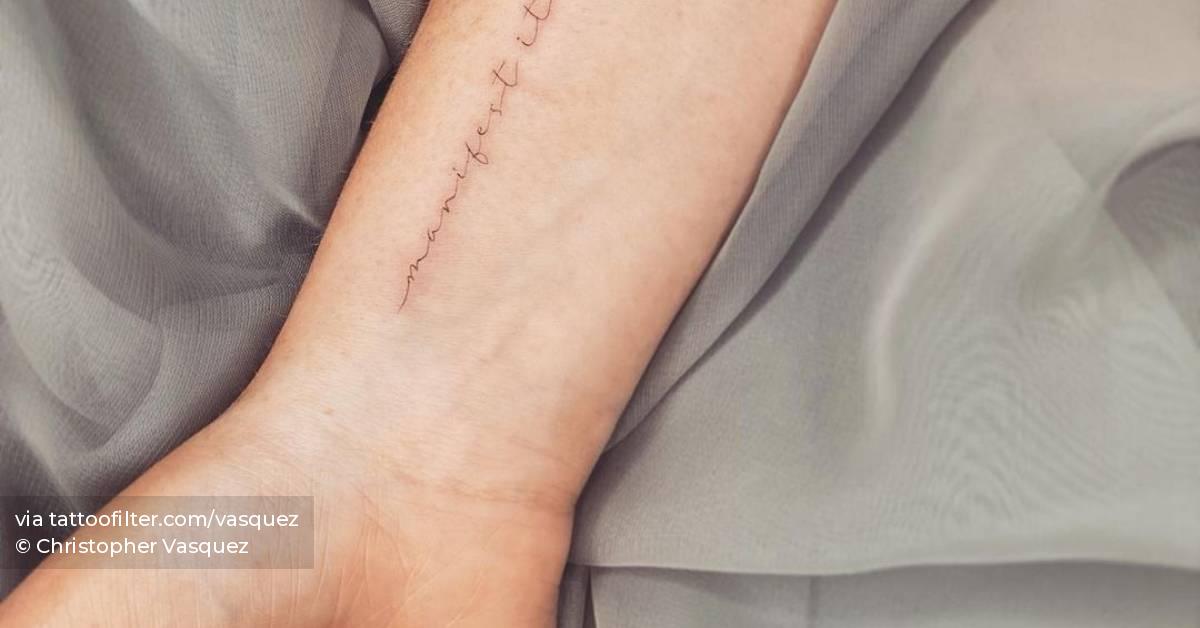 "Manifest it" lettering tattoo on the wrist.
