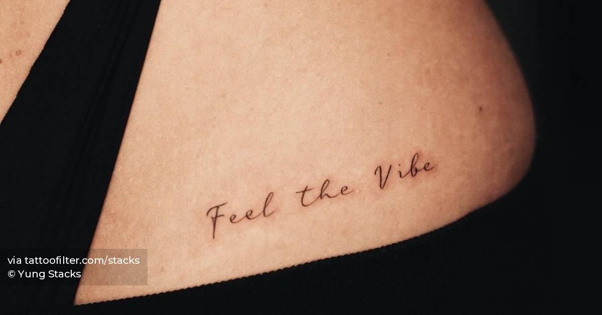 "Feel the vibe" lettering tattoo on the pelvis.