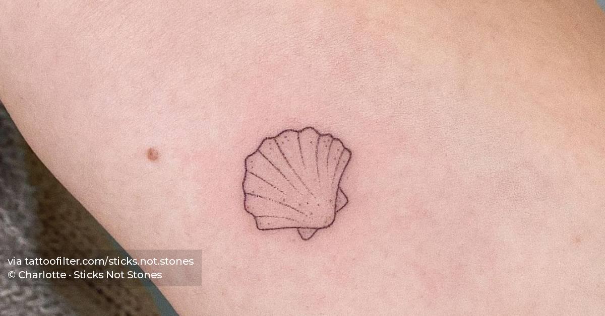 Fine line shell tattoo on the inner forearm.