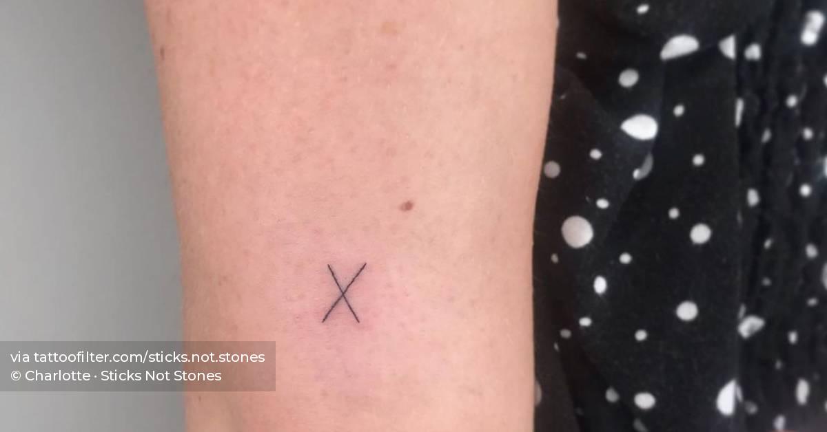 Minimalist letter "X" tattoo hand poked on the tricep.