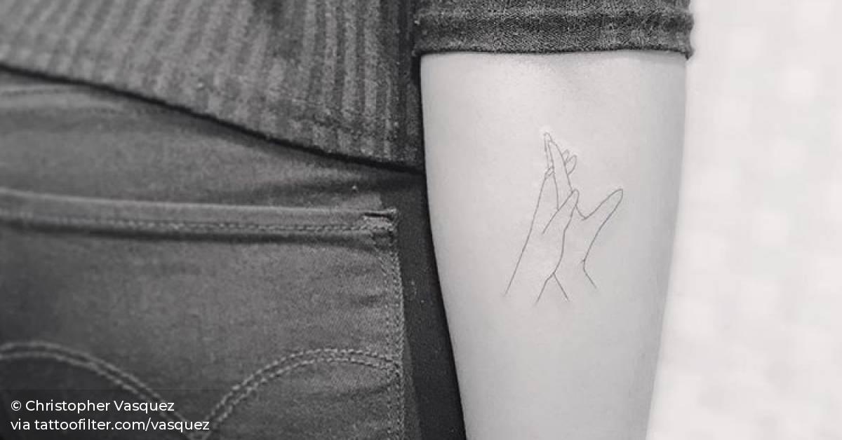 Clasping hands tattoo on the right forearm.