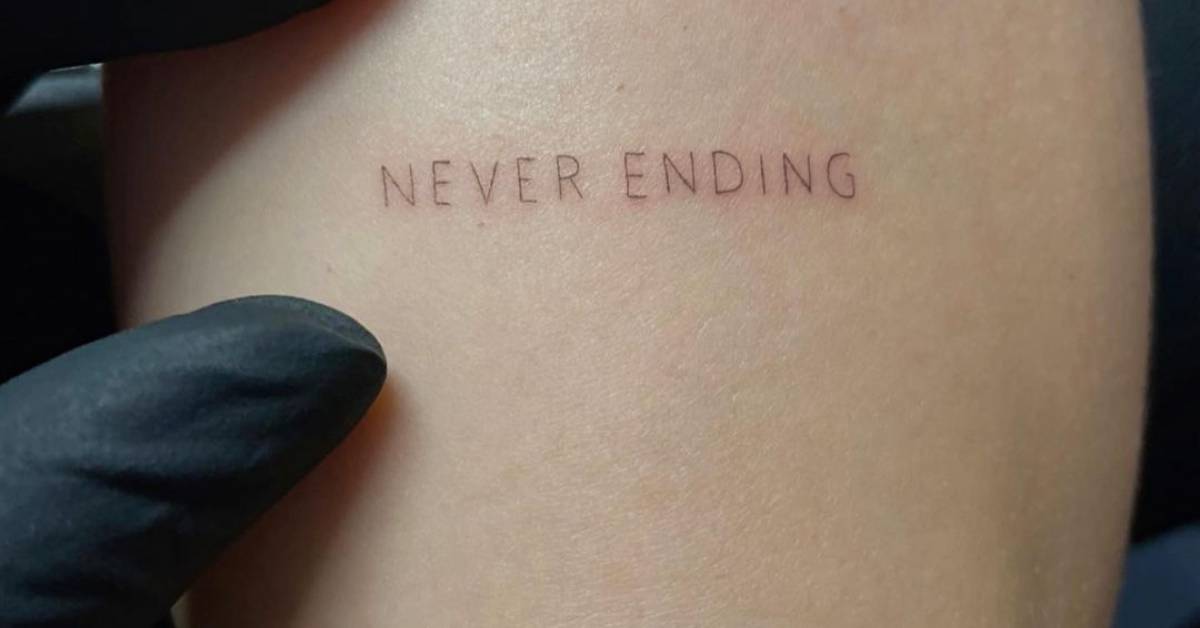 Tattoo that says "never ending" written on the tricep.