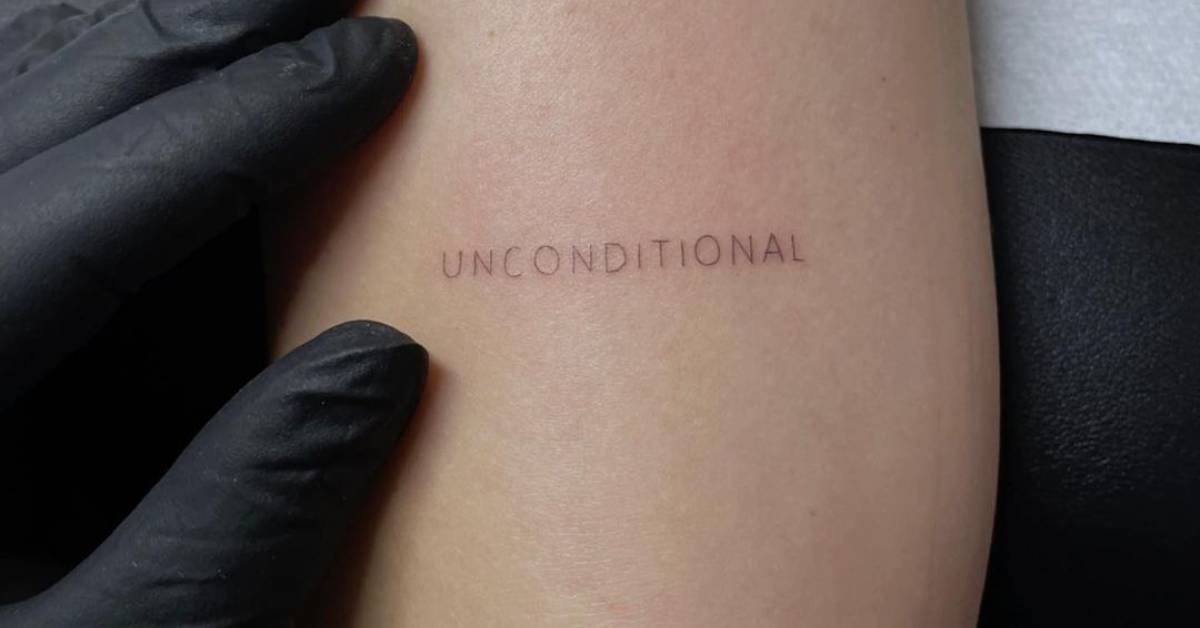 Word "unconditional" tattooed on the tricep.