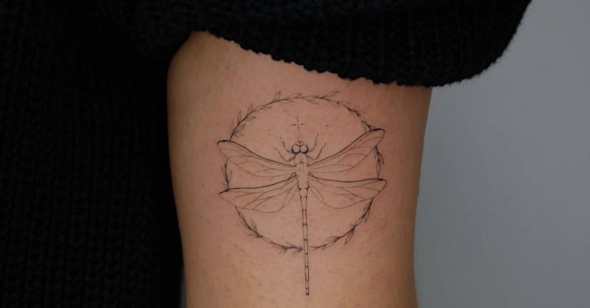 Fine line dragonfly tattooed on the tricep.