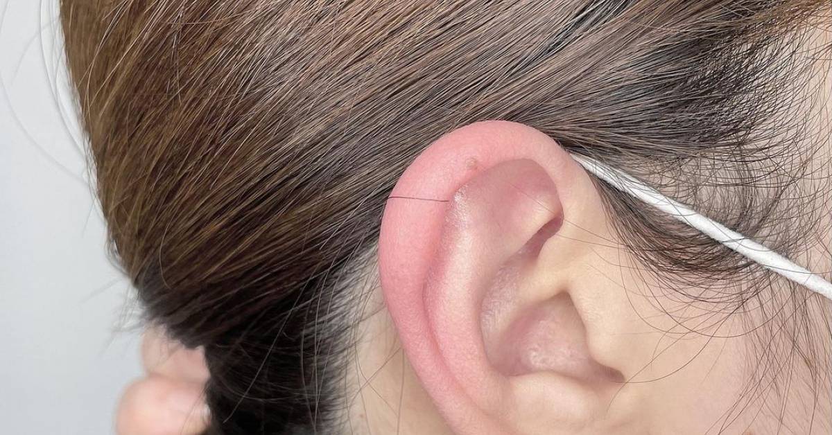 Minimalistic line tattoo on the ear helix.