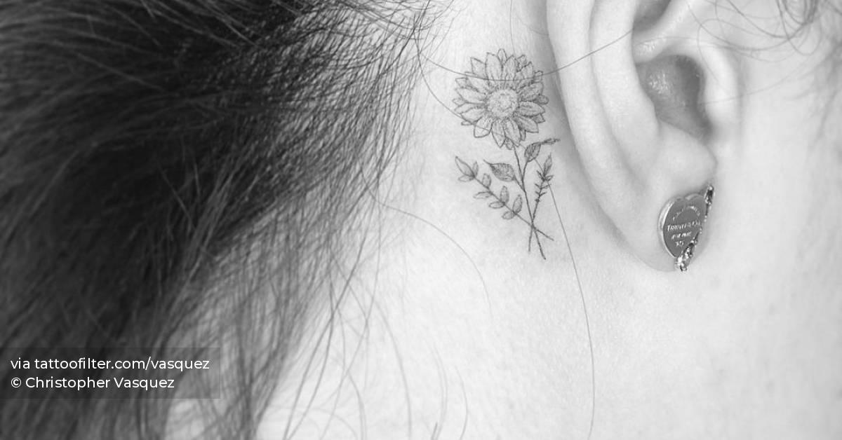 Micro-realistic sunflower tattooed behind the ear.