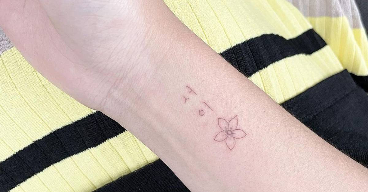 Fine line flower and lettering tattoo located on the