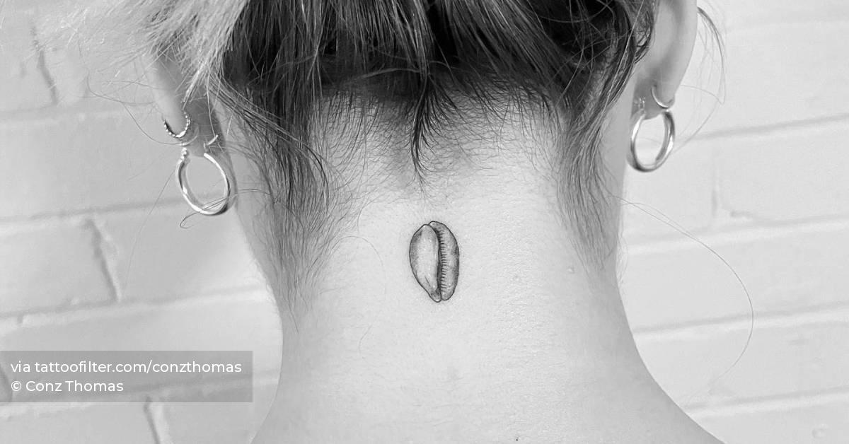 Tiny cowrie shell tattoo done on the back of the neck.