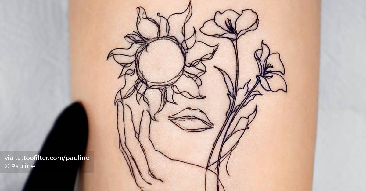 Flower head woman tattoo located on the inner arm.