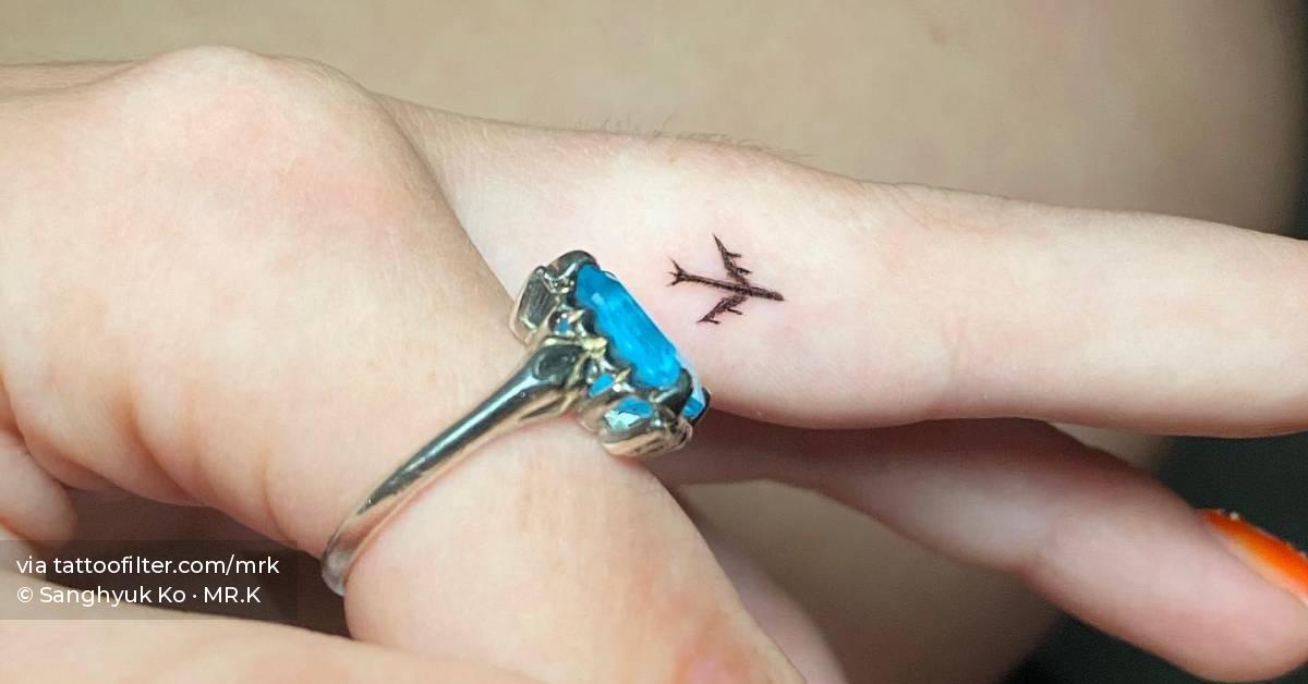 Tiny airplane tattoo located on the finger.