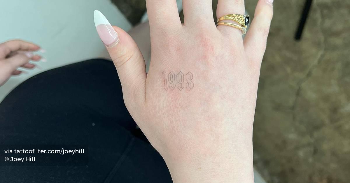 "1998" tattoo located on the hand.
