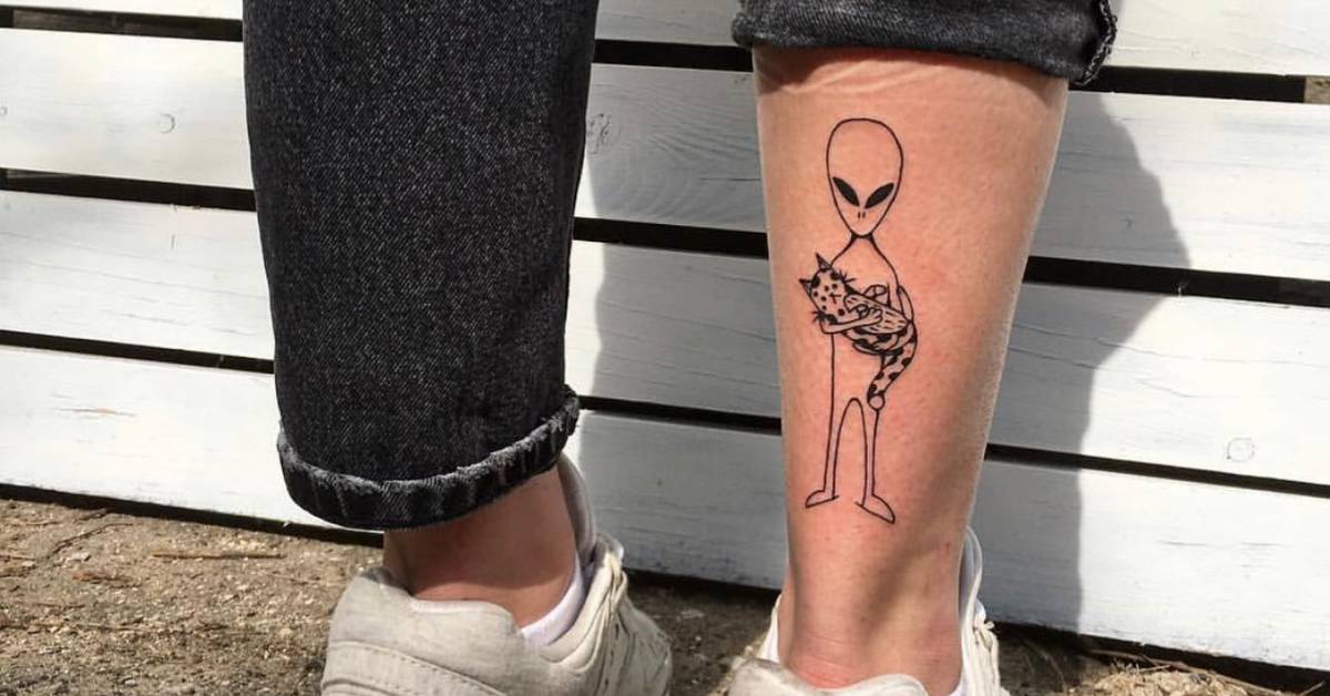 Alien holding a cat tattooed on the achilles.