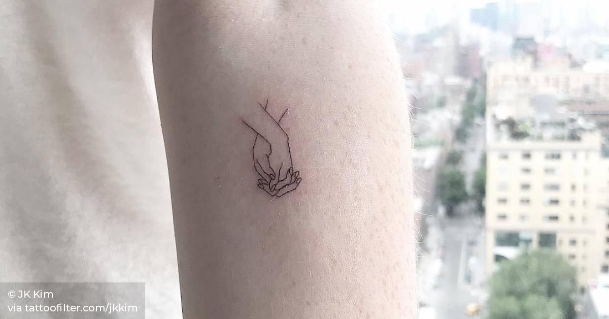 Fine line holding hands tattoo on the inner forearm.