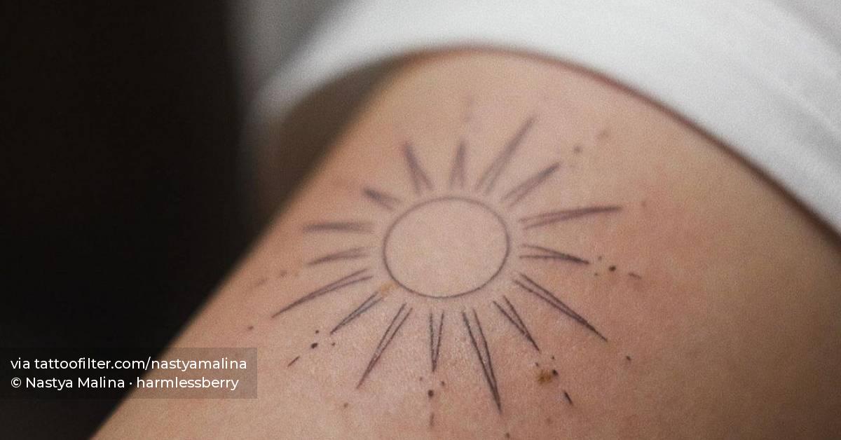 Fine line sun tattoo on the bicep.