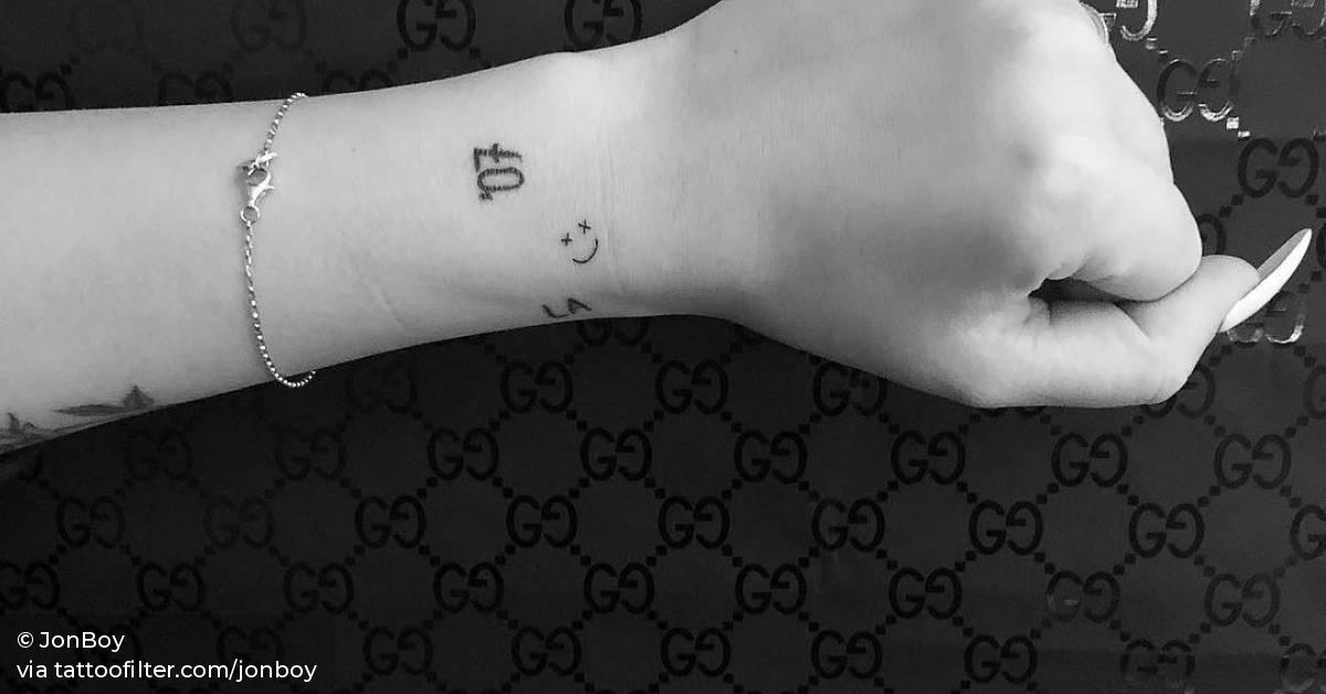 Minimalist emoji tattoo on the wrist.
