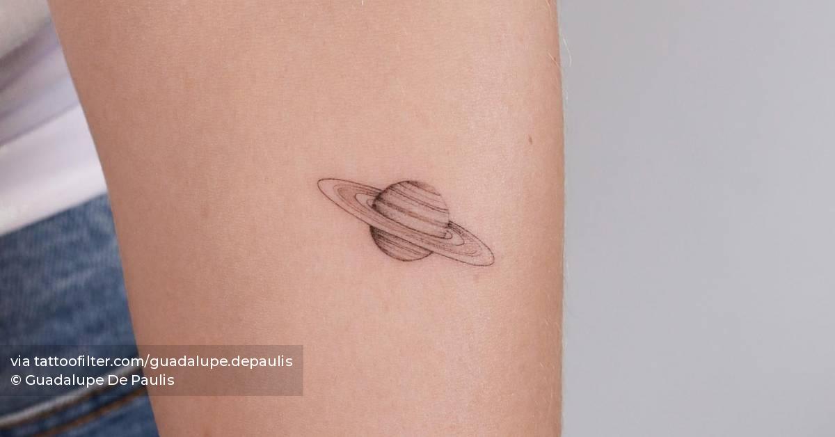 Fine line Saturn tattooed on the inner forearm.