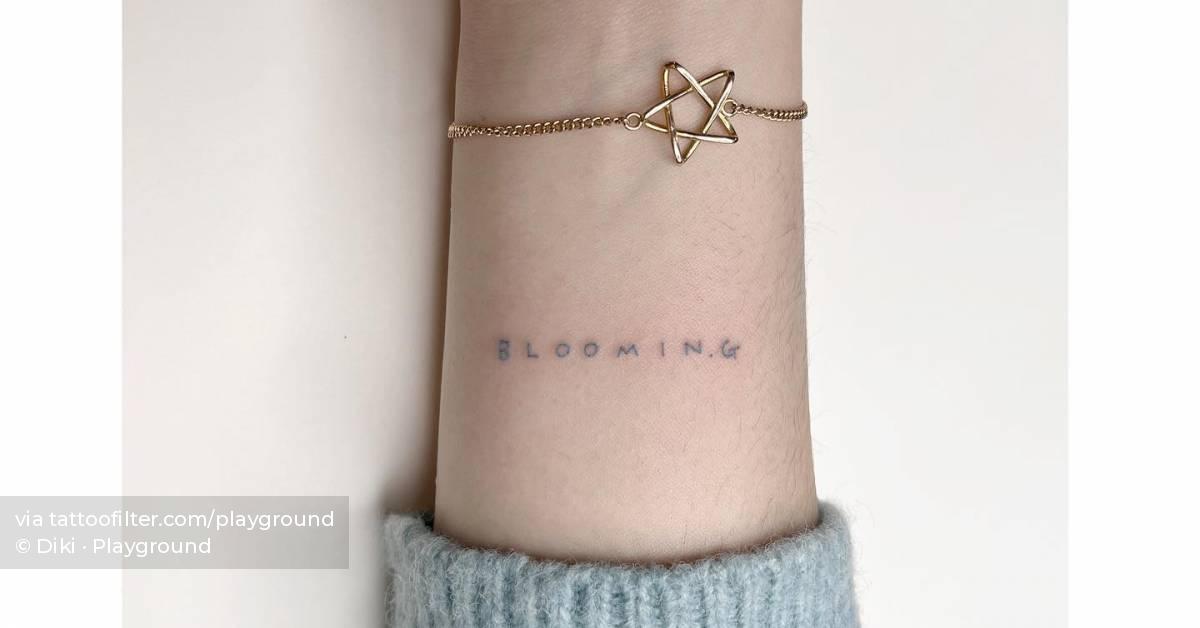 Word "blooming" tattooed in blue ink.
