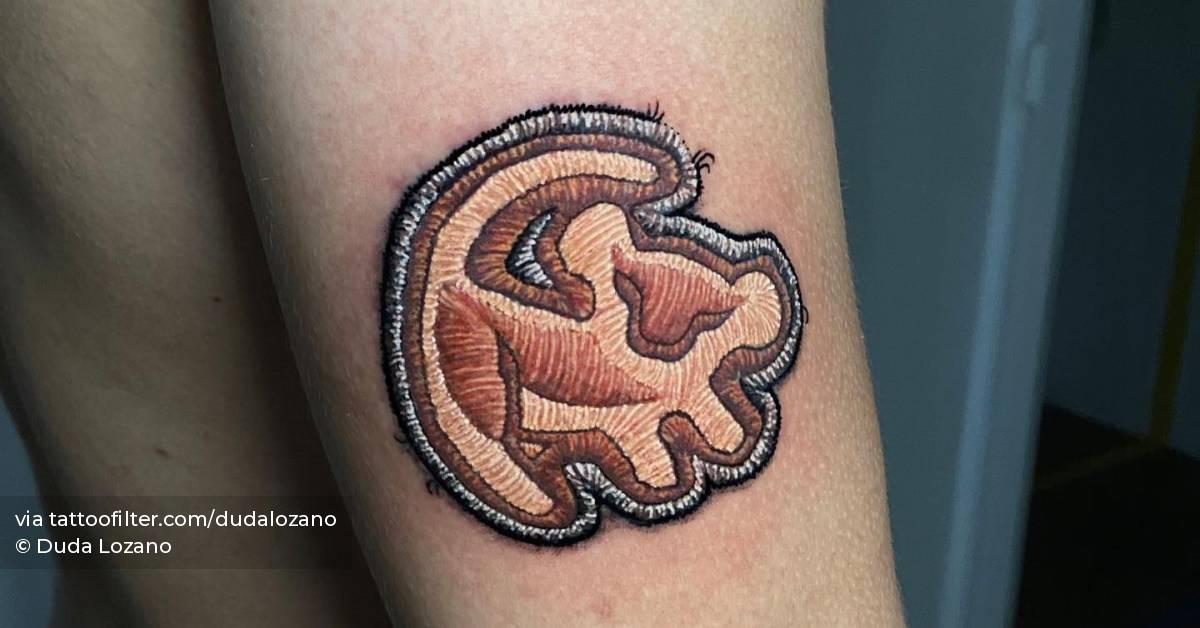 Simba patch tattooed on the upper arm.