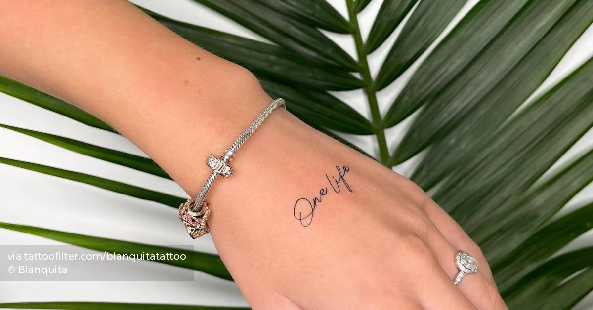 Tattoo that says "one life" handwritten on the hand.