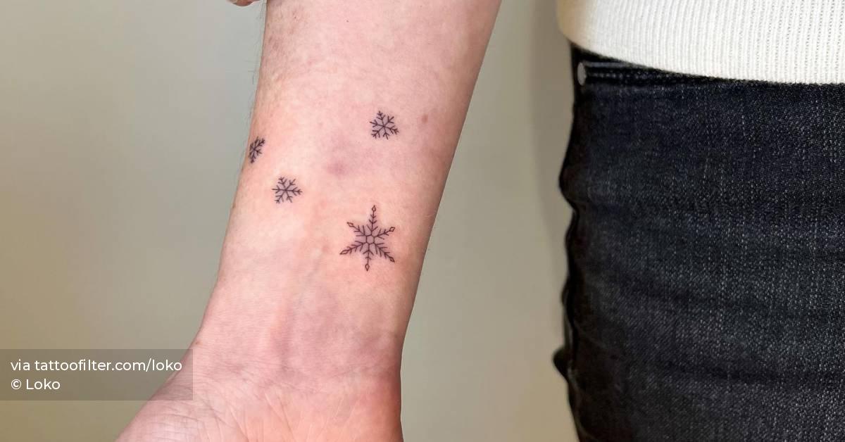 Fine line snowflakes tattooed on the wrist.
